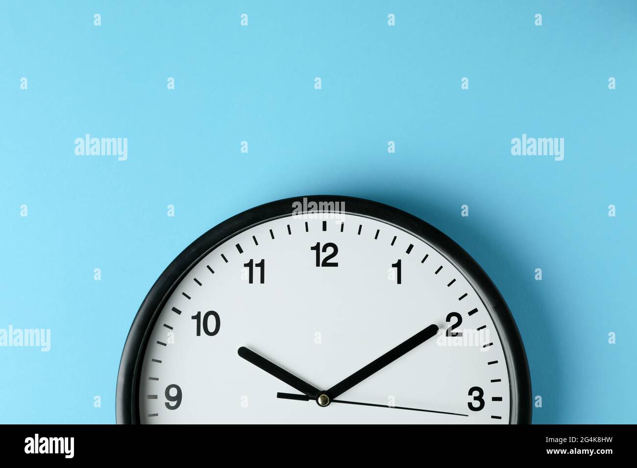 Standard black office clock on blue background Stock Photo - Alamy