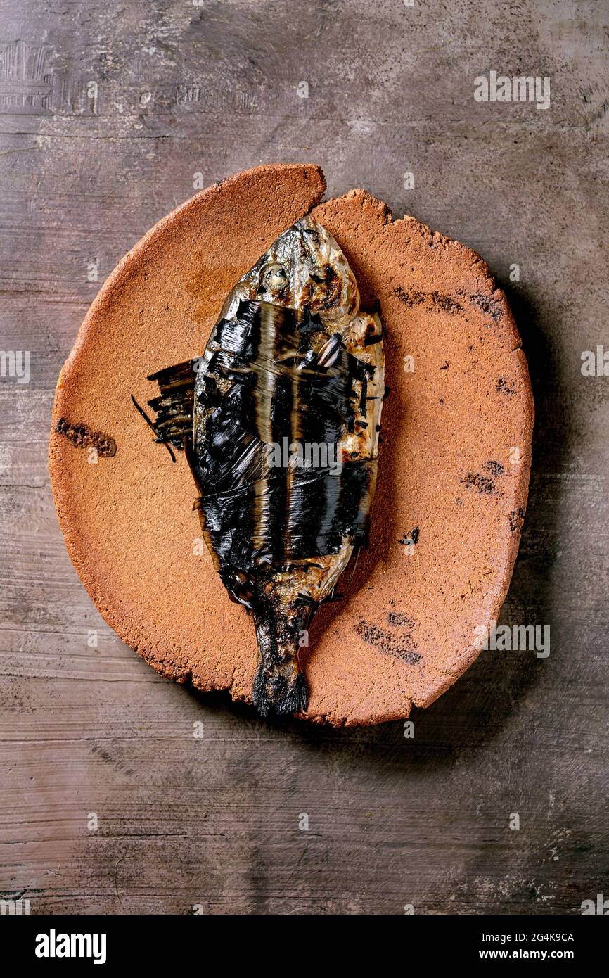 Grilled cooked fresh gutted sea bream or dorado fish on ceramic plate ...