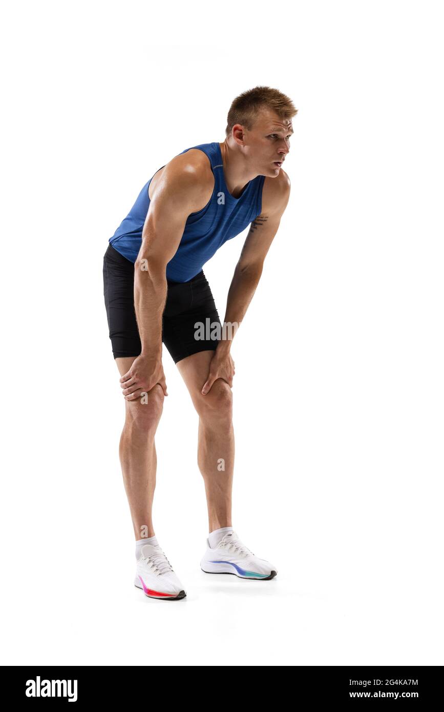 Caucasian professional male athlete, runner standing isolated on white ...
