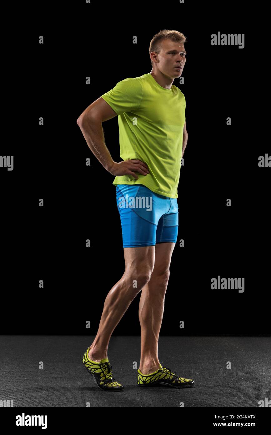 Caucasian professional male athlete, runner standing isolated on black ...
