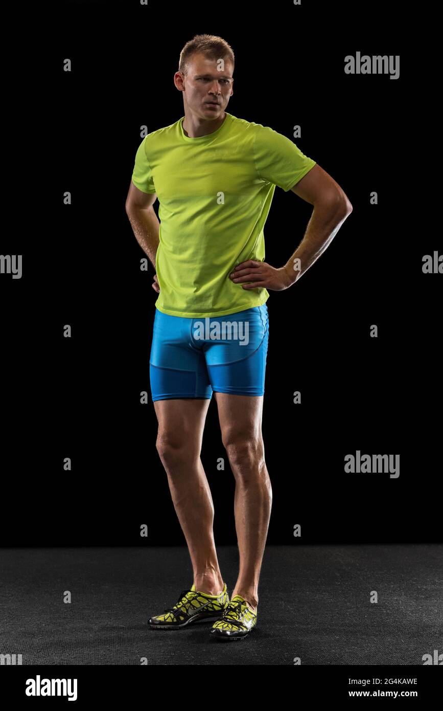 Caucasian professional male athlete, runner standing isolated on black ...