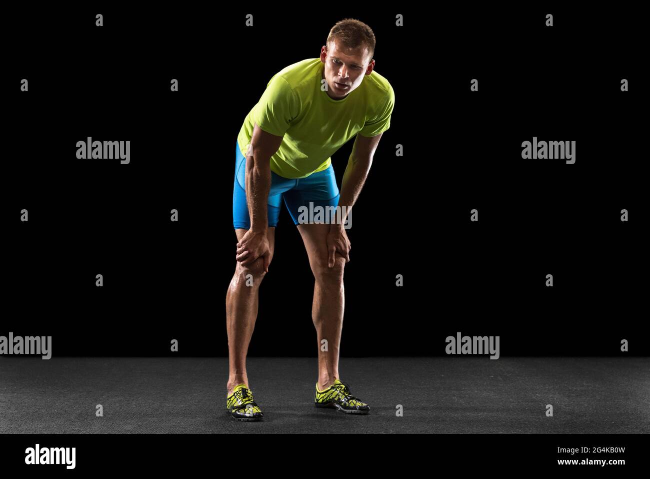Caucasian professional male athlete, runner standing isolated on black ...
