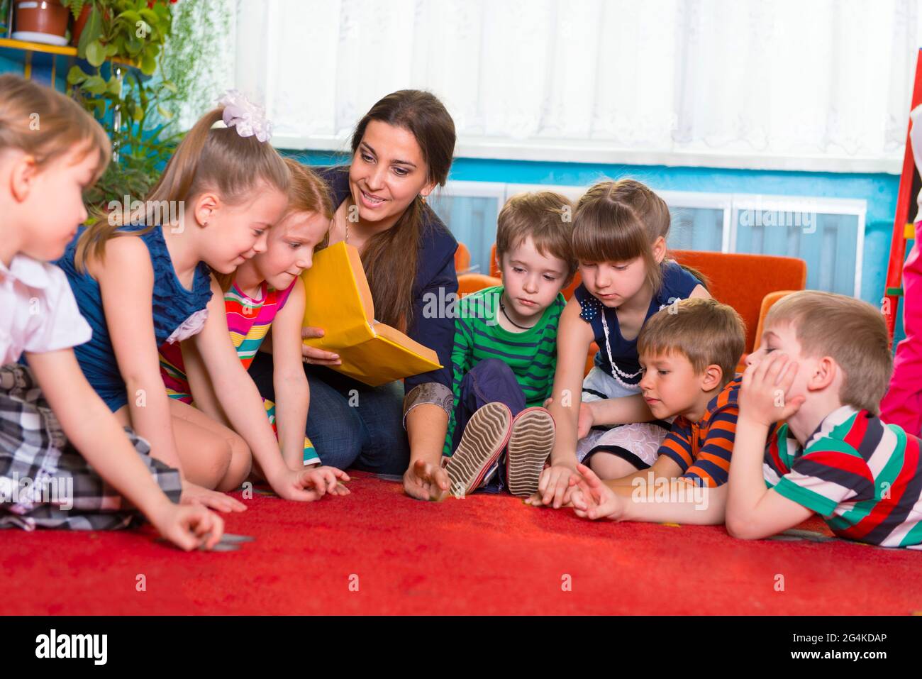 Children with tutor reading book at kindergarten Stock Photo - Alamy