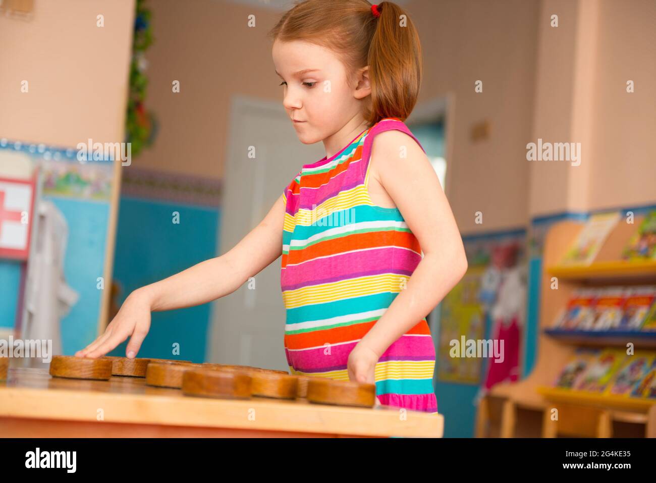 Redhead little girl playing checkers at daycare Stock Photo - Alamy