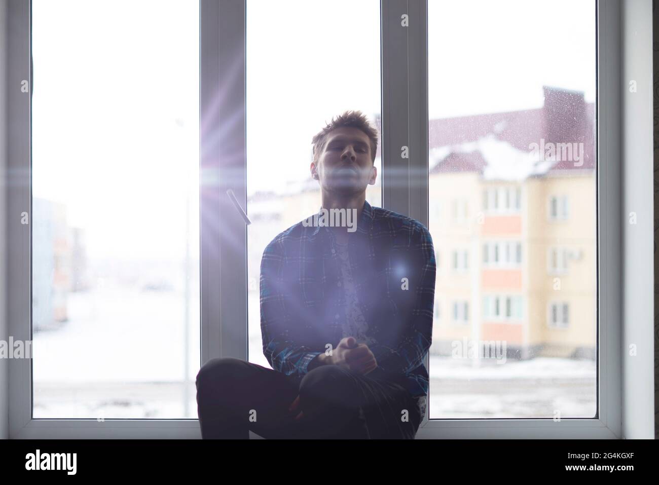 sad lonely thoughtful man silhouette sitting on a window windowsill and ...