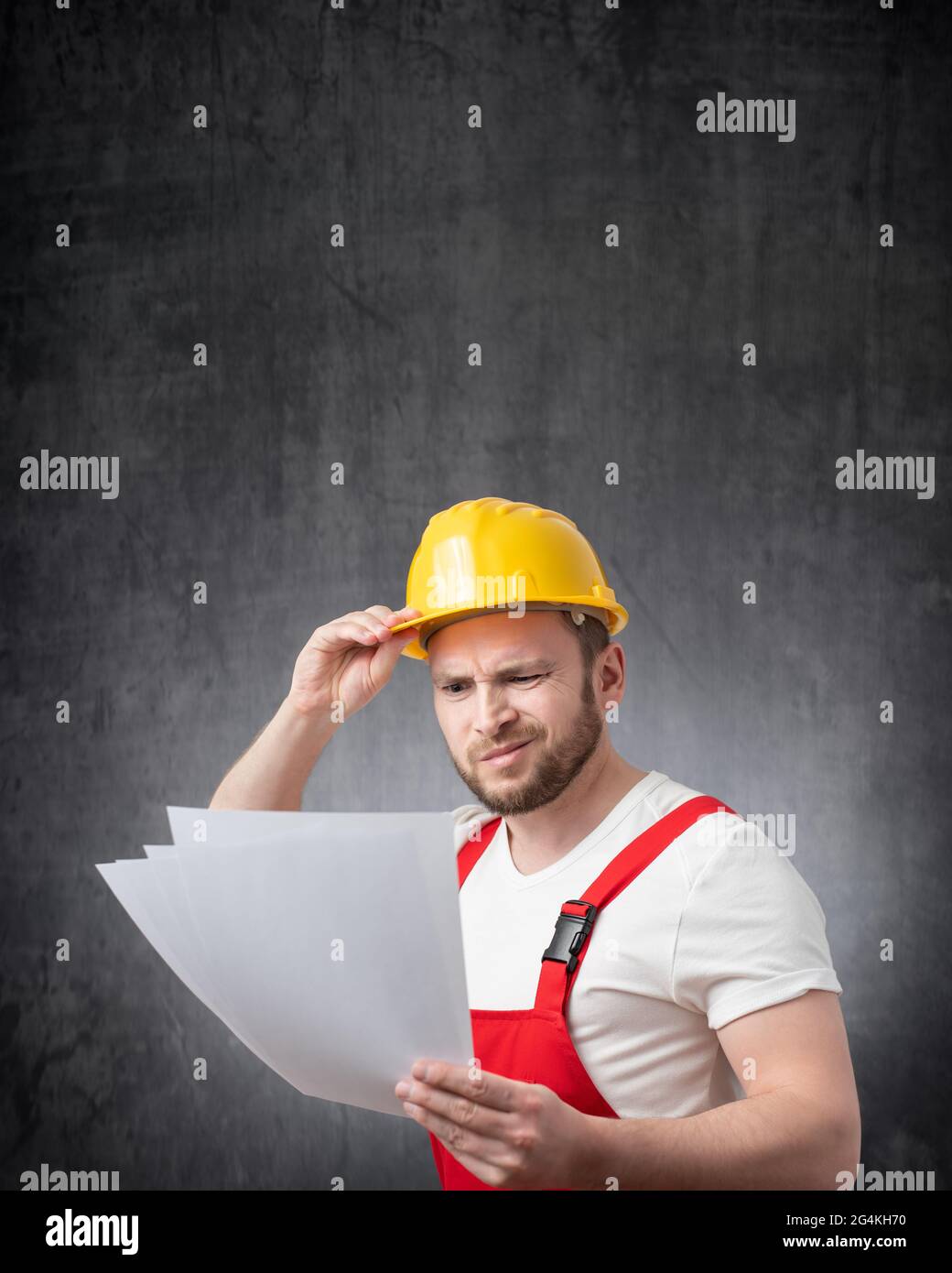 A confused construction worker holding papers or documents Stock Photo ...