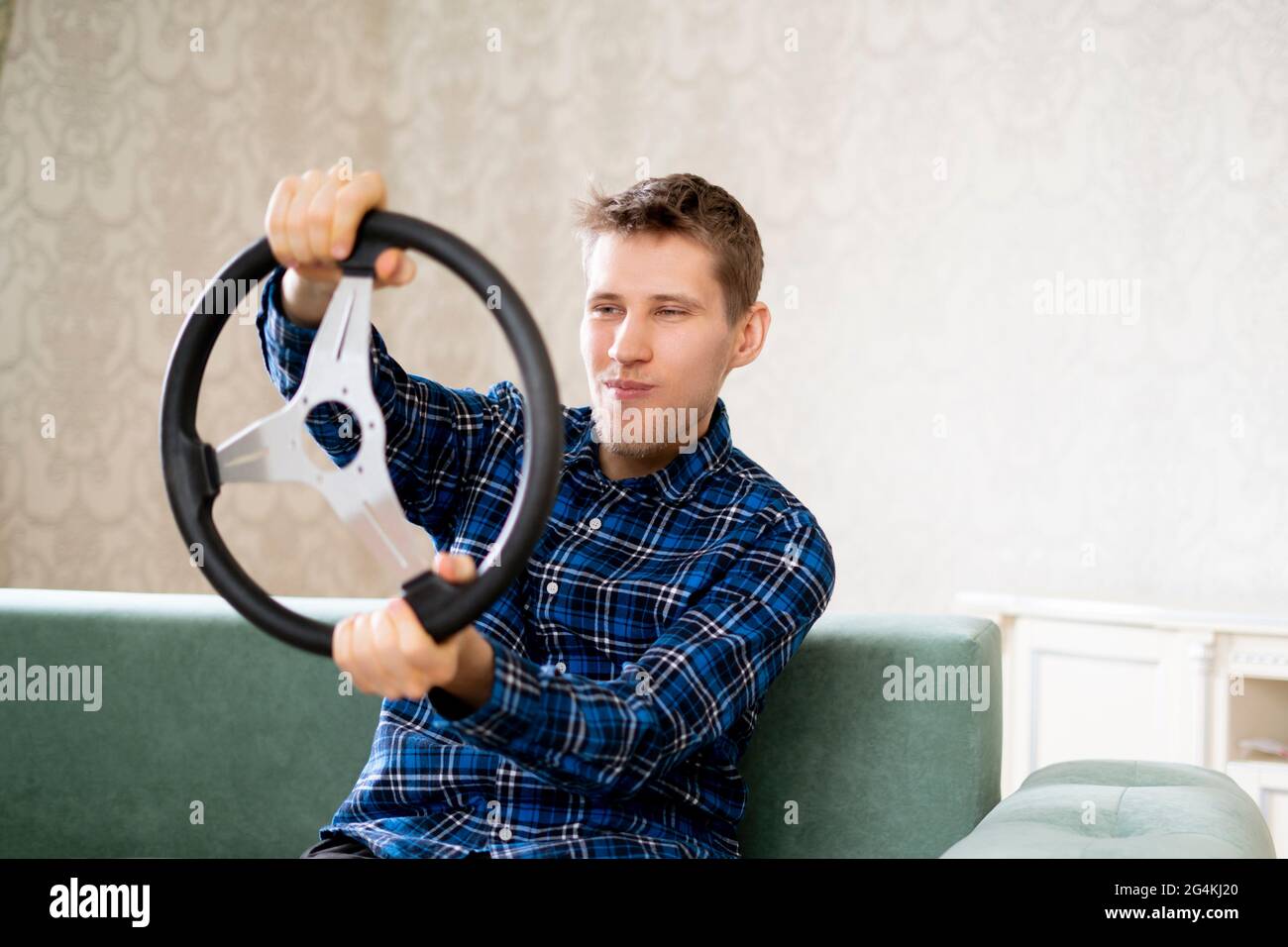 young man hold a steering wheel and imagine himself as a race driver ...