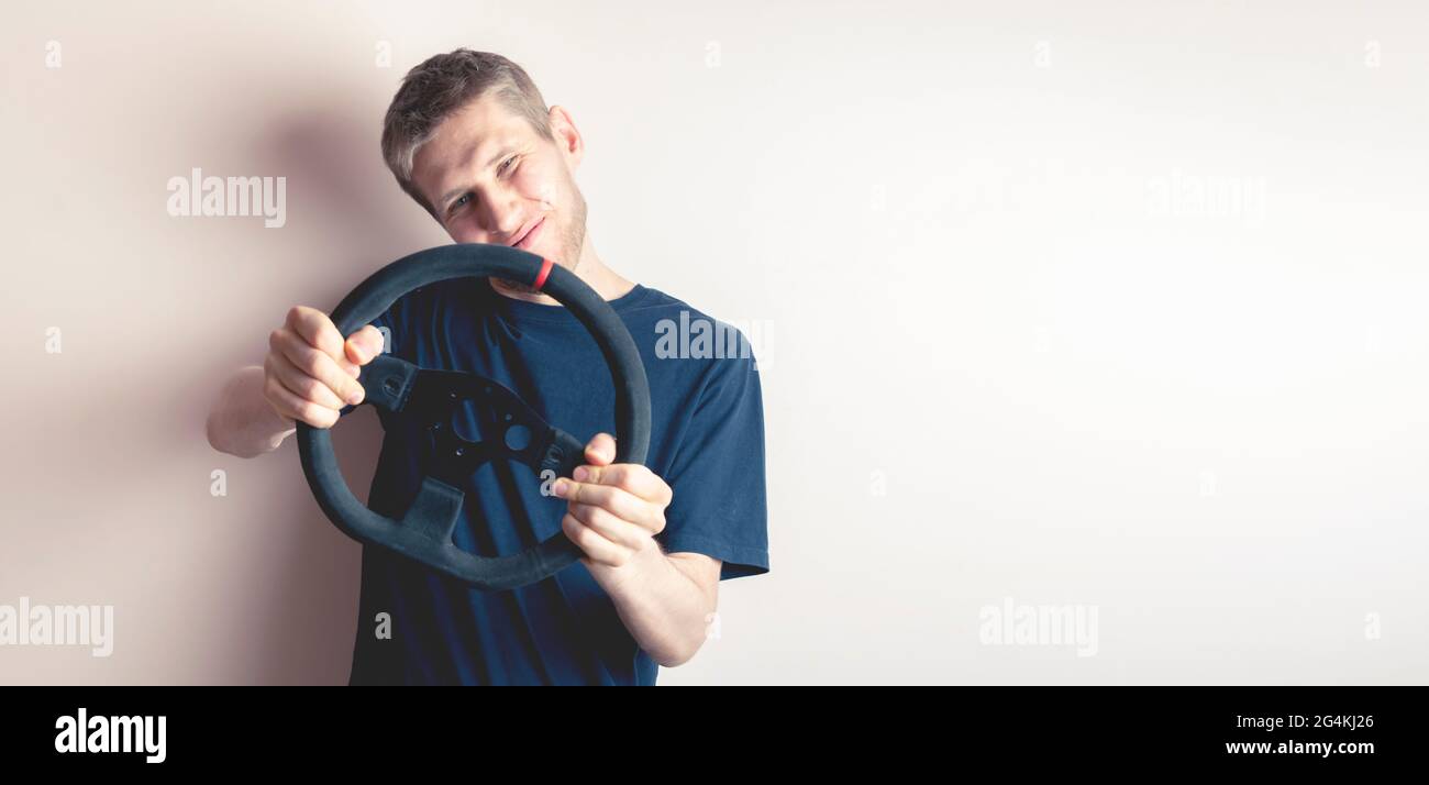 young man hold a steering wheel and imagine himself as a race driver ...