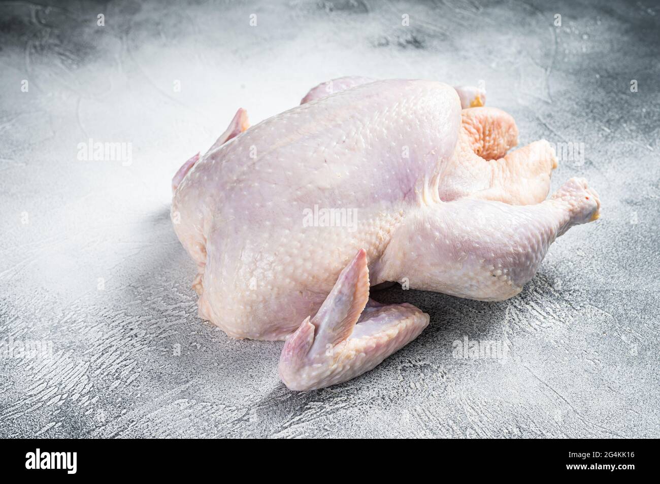 Raw free range whole chicken on a kitchen table. White background. Top ...