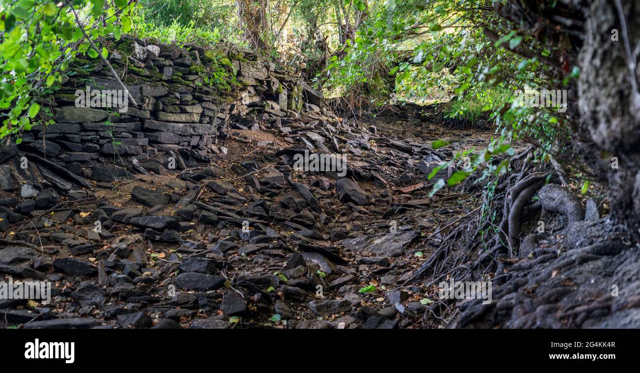 Dry river banks full of dark stones Stock Photo - Alamy