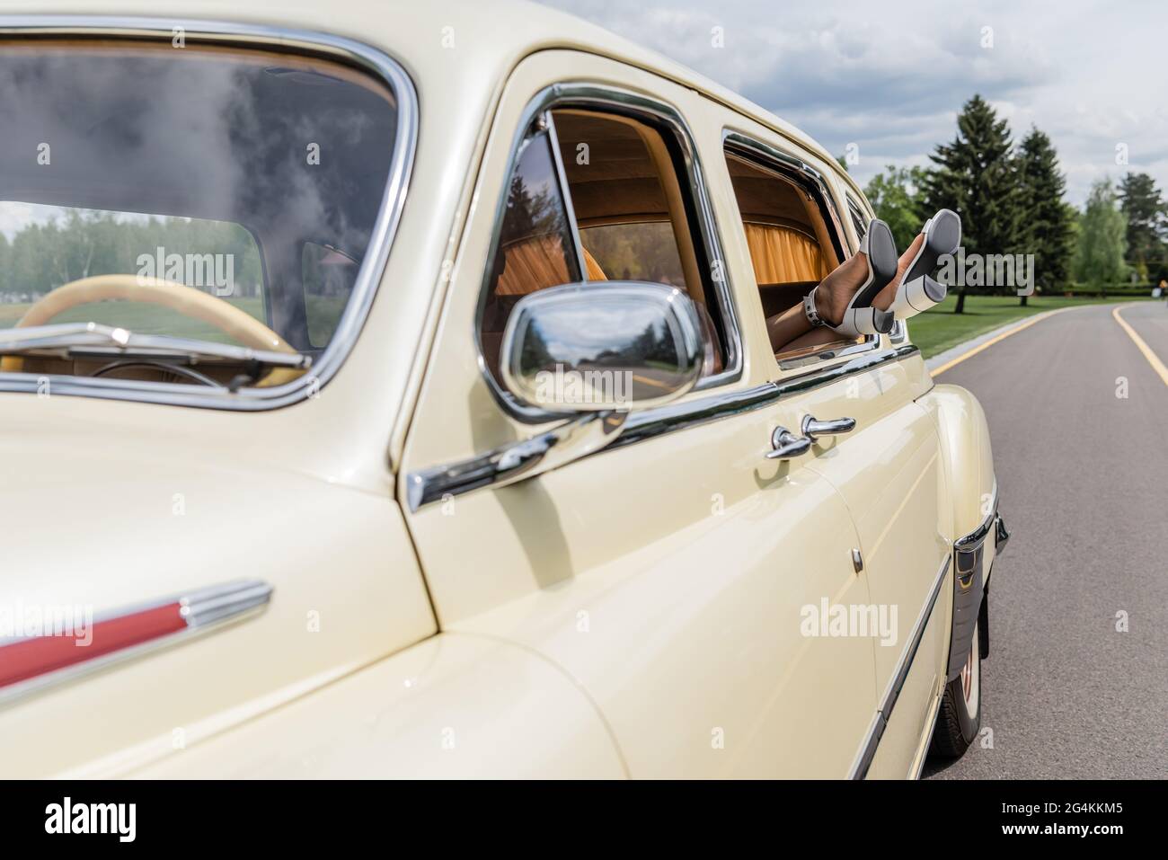 Cropped view of female legs in window of vintage car on road Stock ...