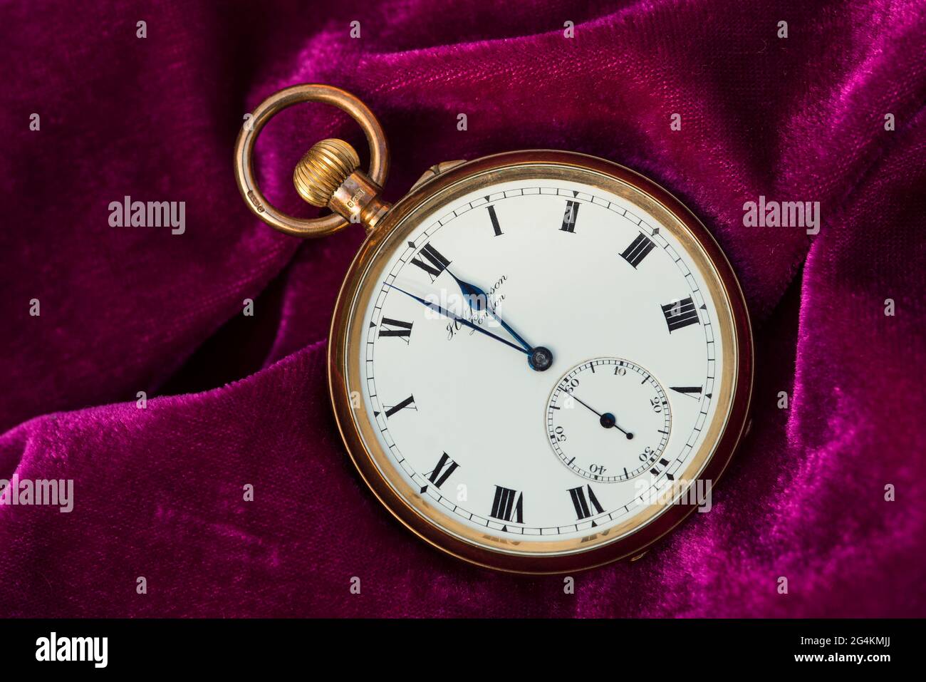 Two minutes to midnight. Close up of a pocket watch on magenta velvet ...
