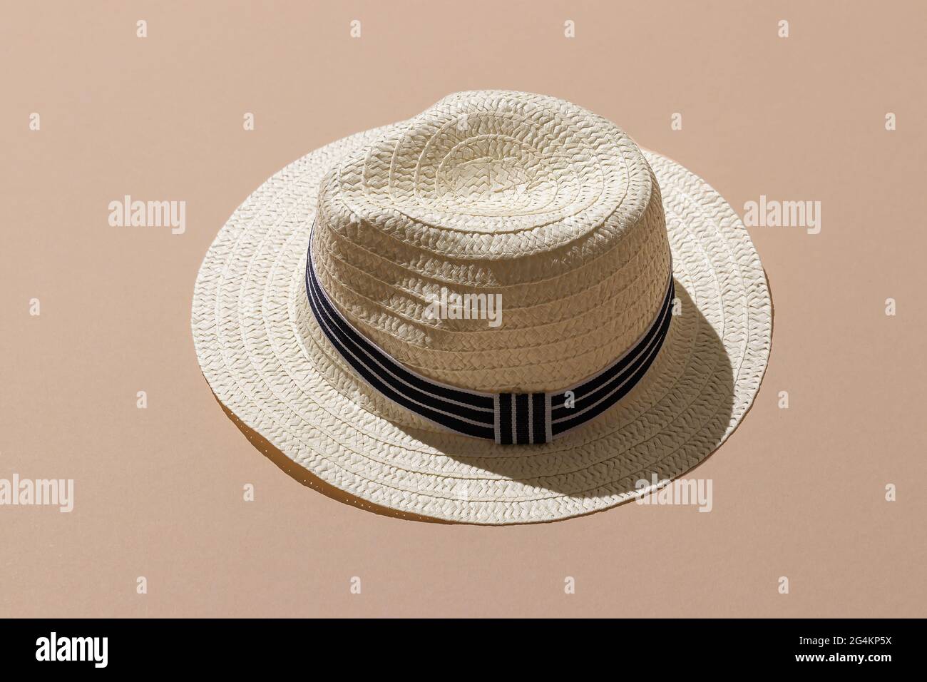 white straw wicker hat on a sand color background. hard shadows of the ...