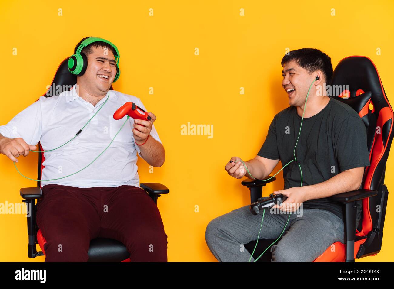 Two guys laugh and play video games with game controllers Stock Photo ...