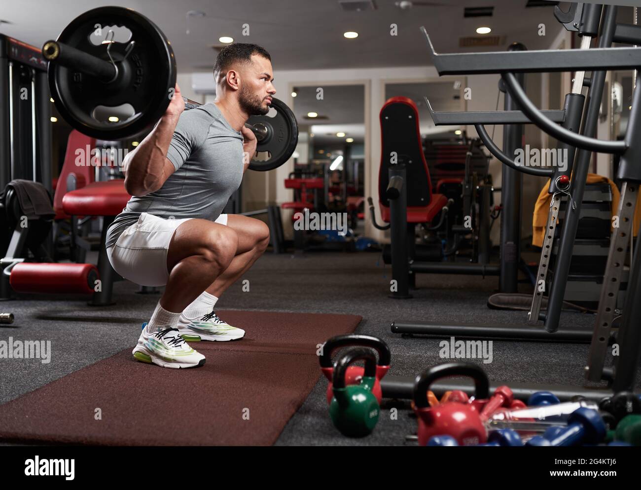 Athletic young man doing barbell squats in the fitness gym Stock Photo ...
