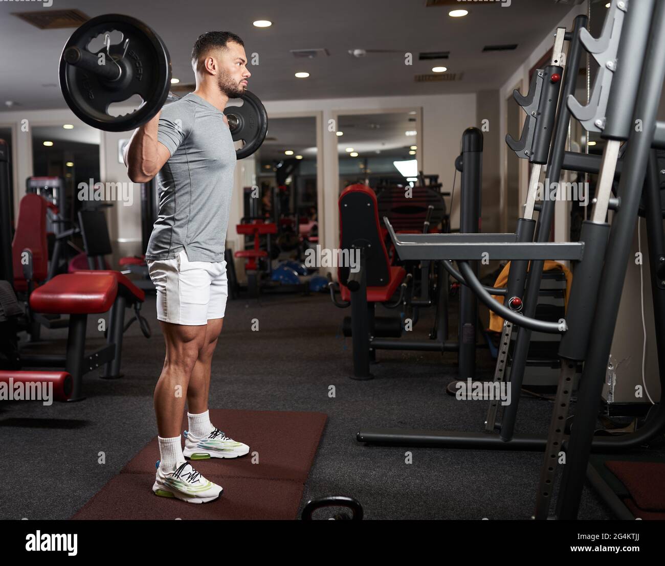 Athletic young man doing barbell squats in the fitness gym Stock Photo ...