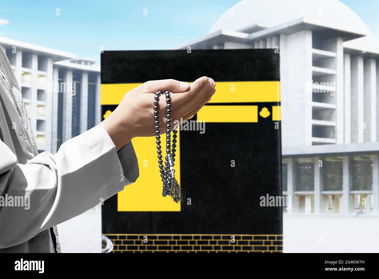 Muslim man praying with prayer beads on his hands in front of the Kaaba ...