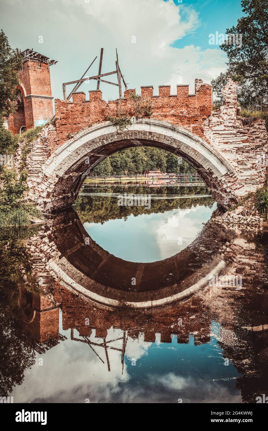 Destroyed gothic arch bridge in an old noble estate with reflection in ...