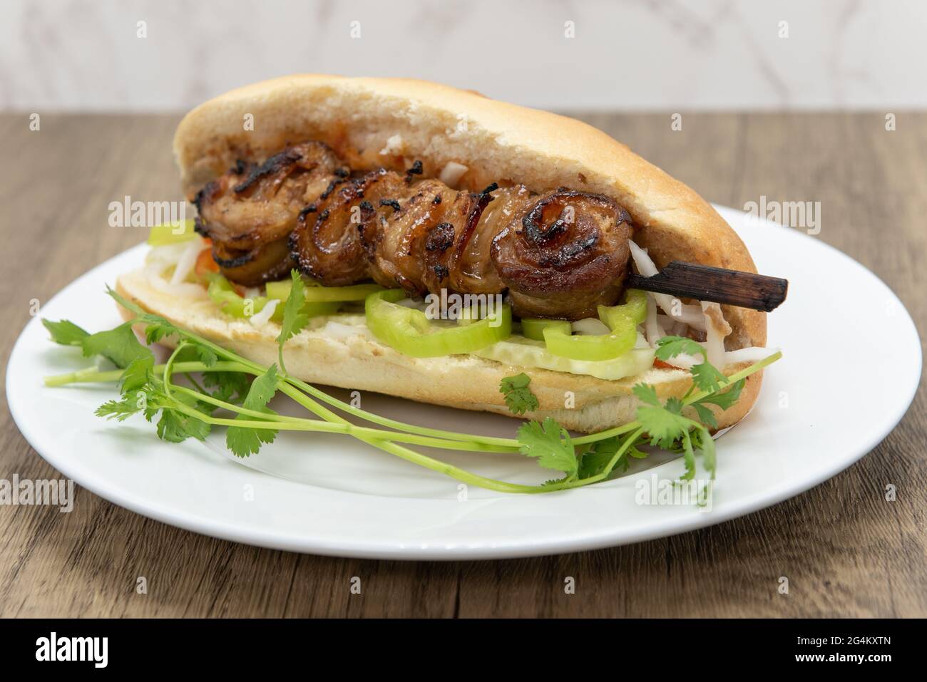 Hearty french bread sandwich loaded with pork belly skewer and ...