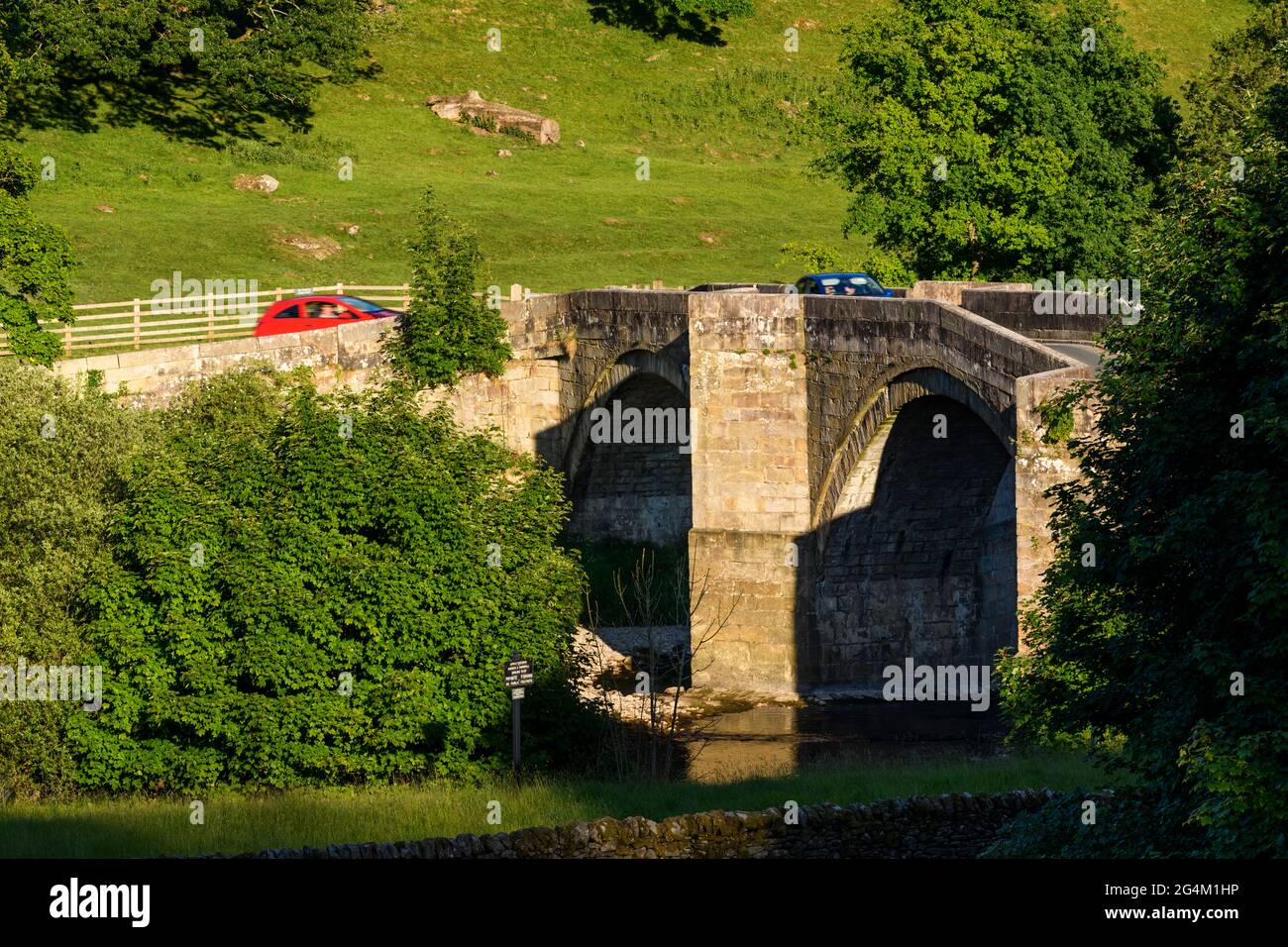 Scenic rural riverside view of historic, stone, arched bridge over ...