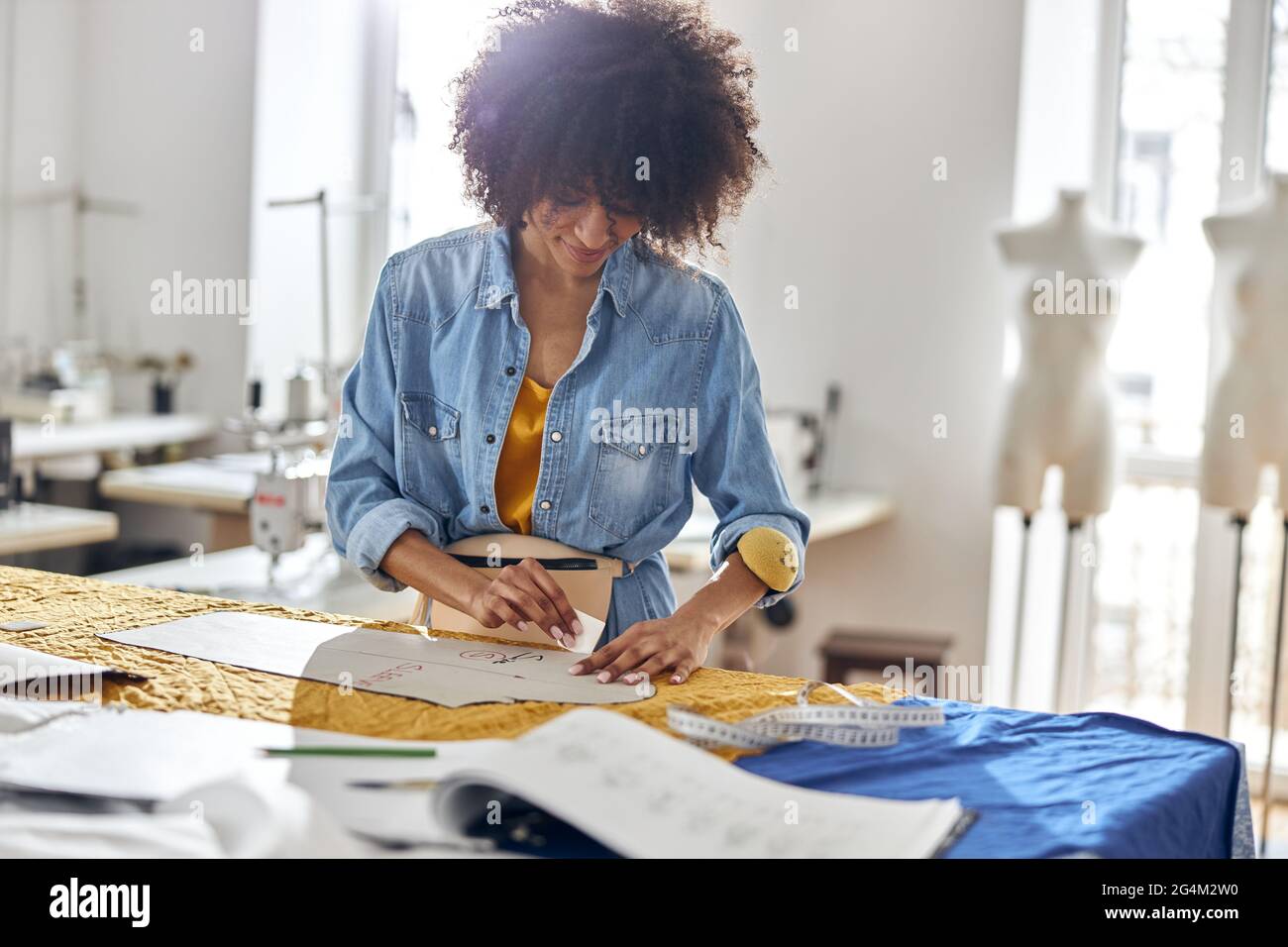 Professional African-American dressmaker draws pattern on fabric ...