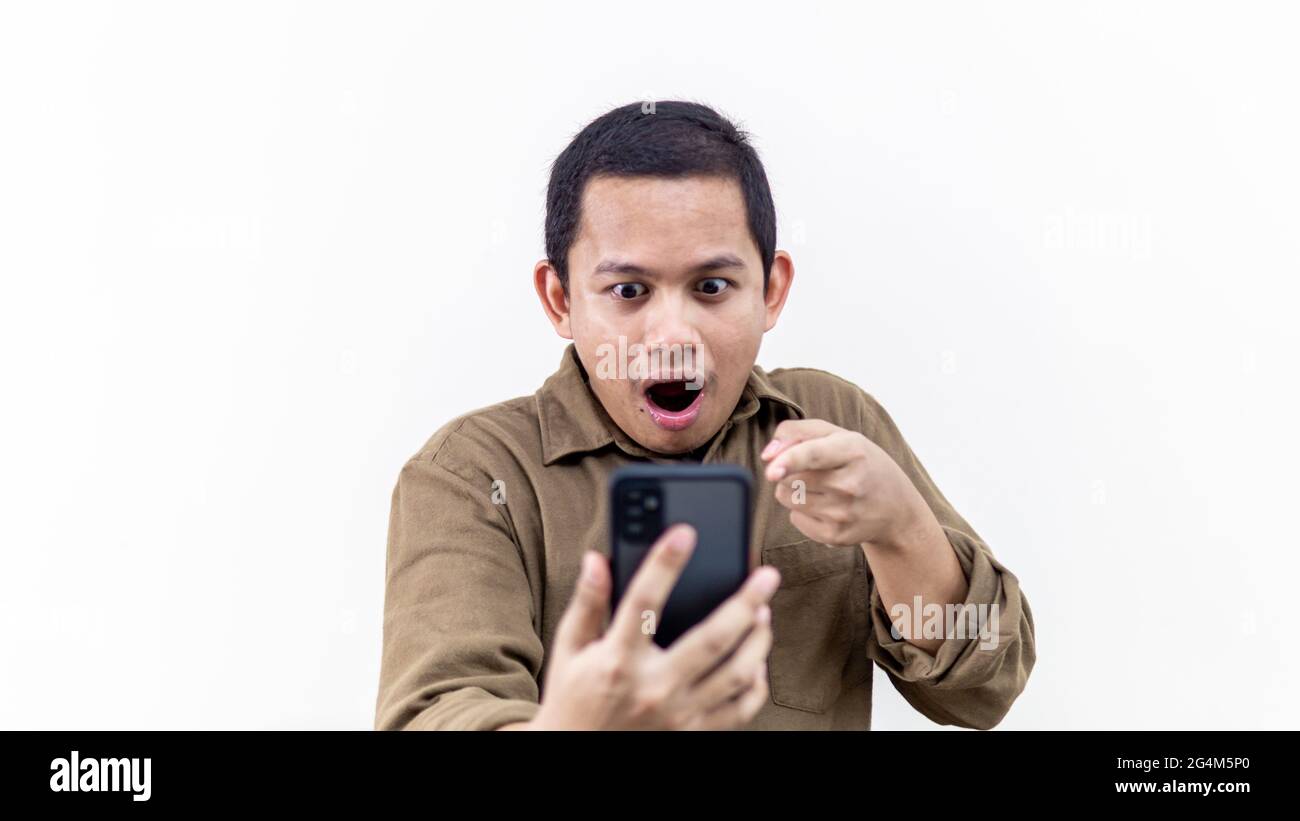 Young Malay looking and pointing at the smartphone screen with a ...