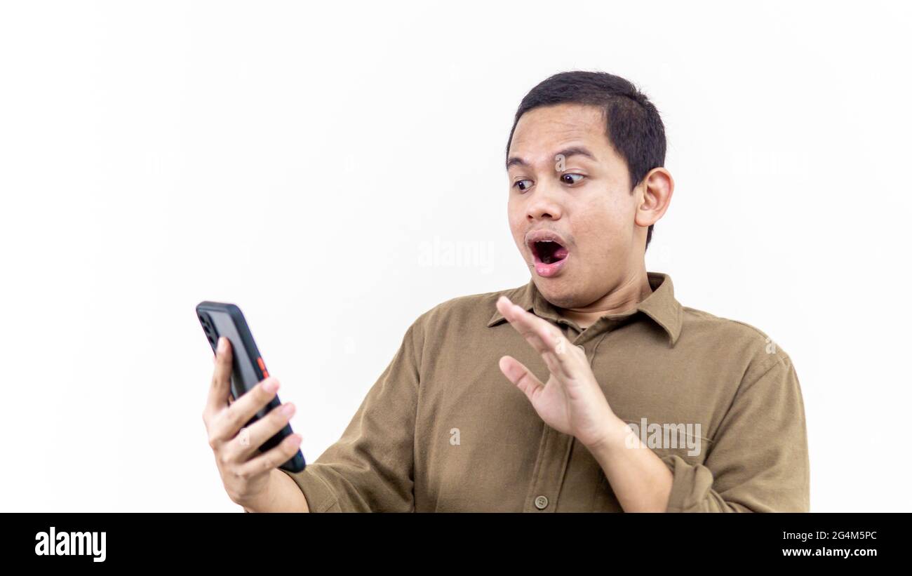 Young Malay looking at the smartphone screen with a shocked face ...