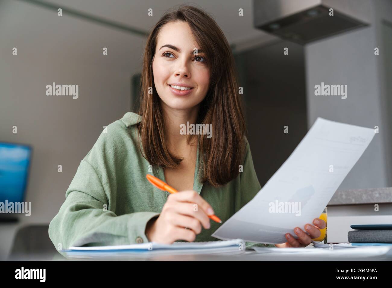 Happy beautiful woman smiling while working with papers at home Stock ...