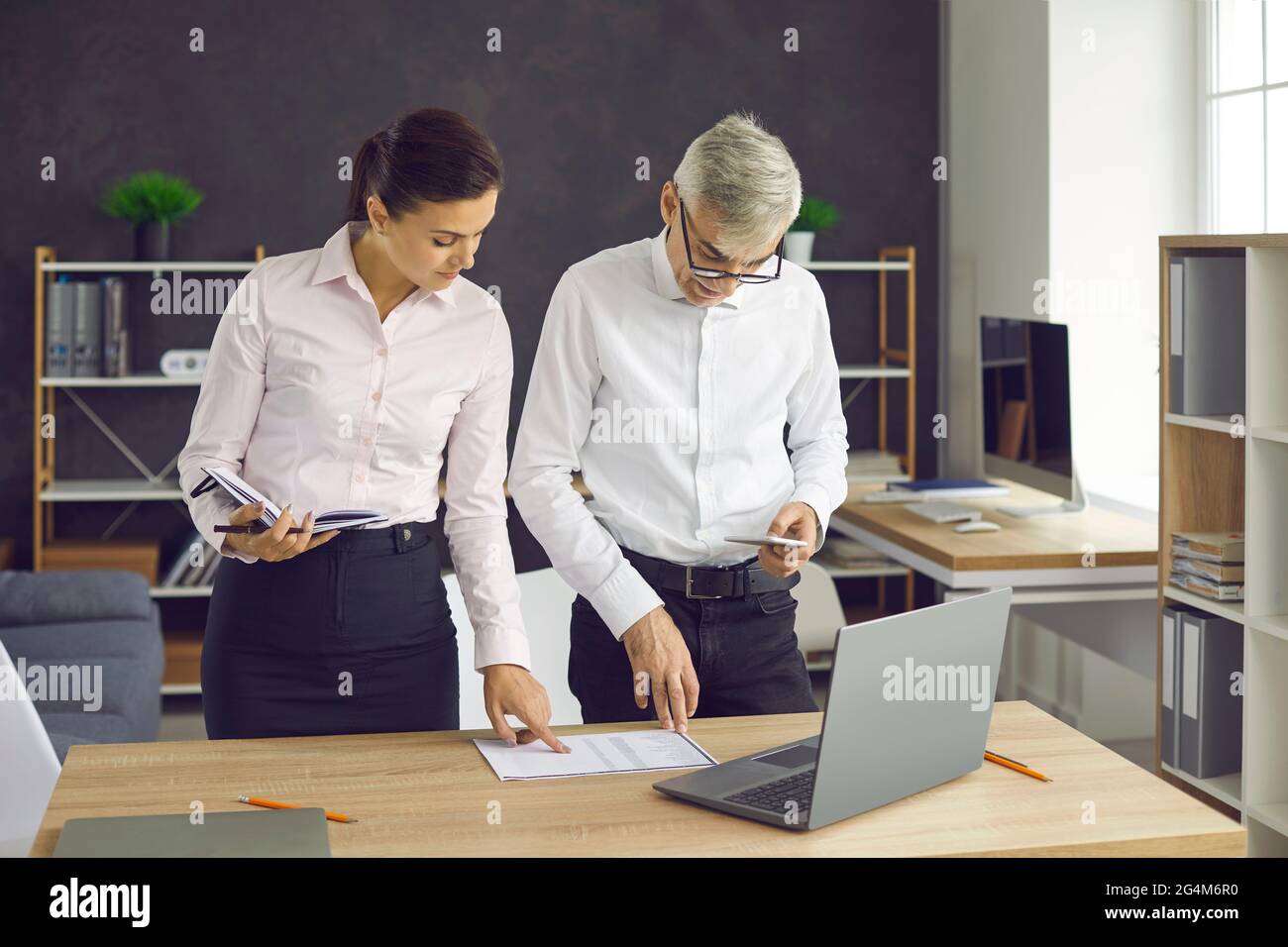Two business colleagues standing by the office desk and working with ...
