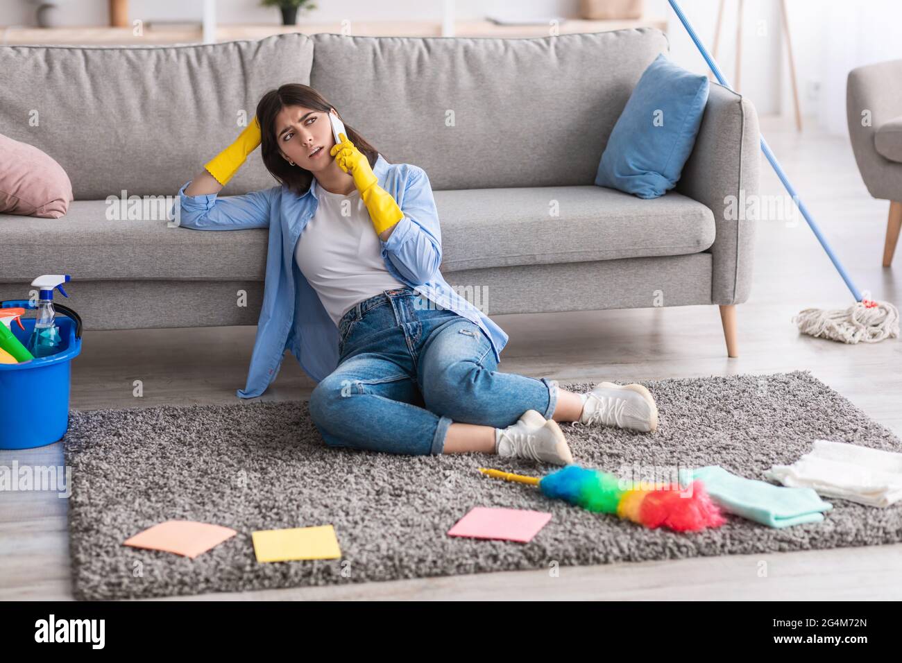 Tired woman talking on phone during cleanup Stock Photo - Alamy
