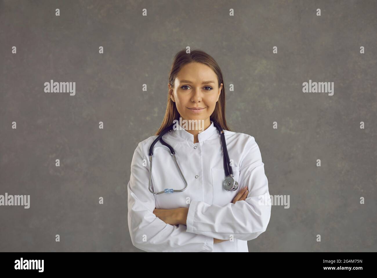 Portrait of a friendly smiling young female medical worker on a gray ...