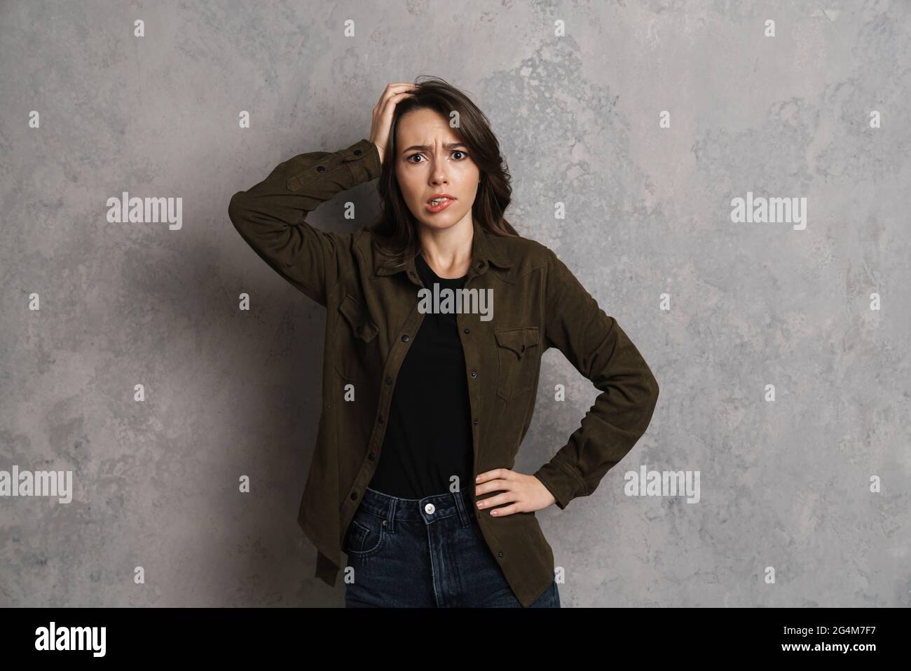 Portrait of a confused young woman looking at camera isolated over gray ...