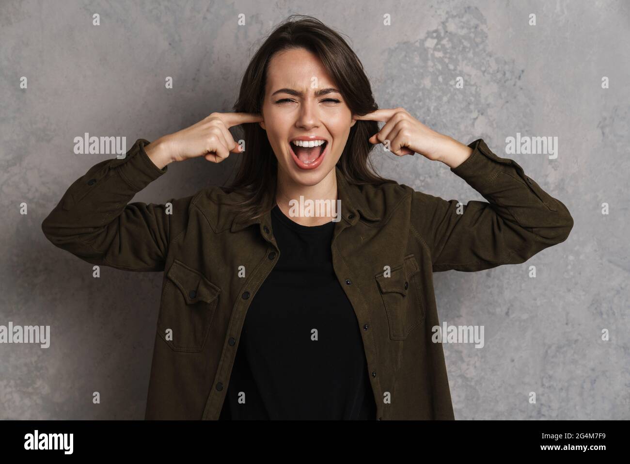 Nervous beautiful girl screaming and plugging her ears isolated over ...