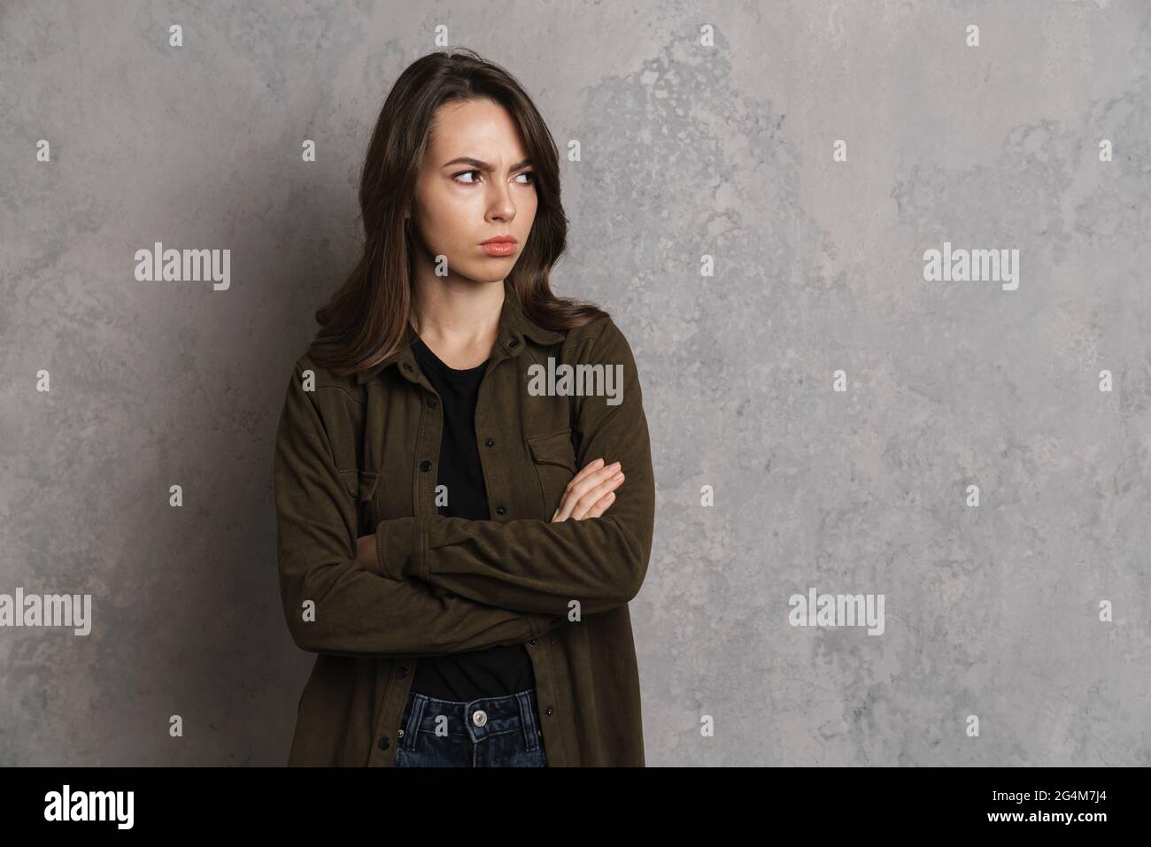 Displeased beautiful brunette girl posing with arms crossed isolated ...