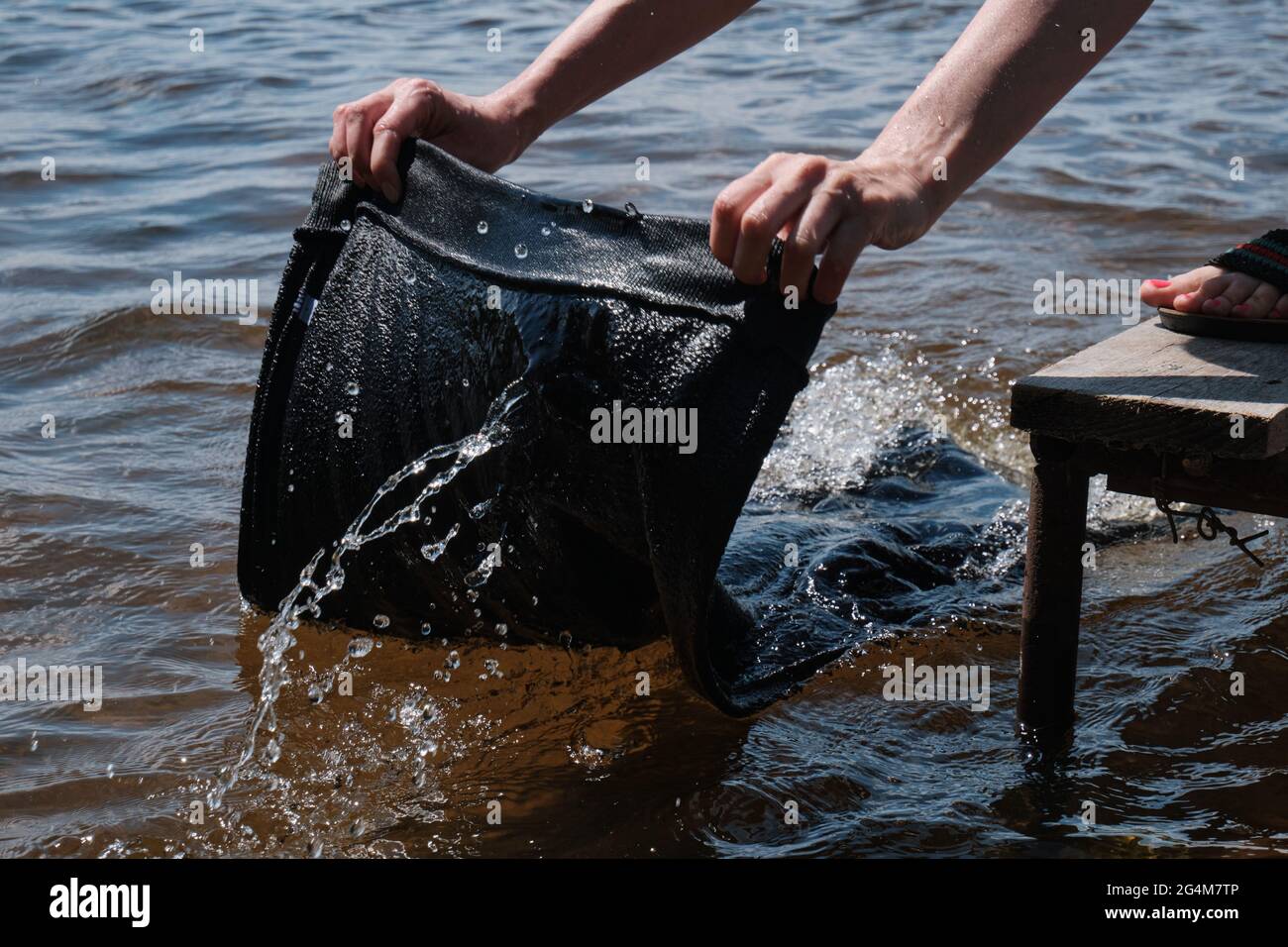 Young girl washes clothes by hand in lake. Hand wash clothes in nature ...