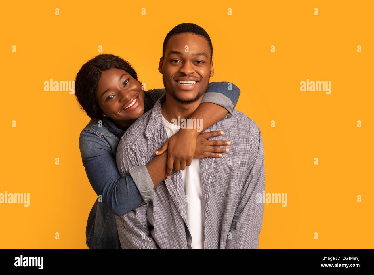 Portrait of young cheerful black couple hugging and smiling at camera ...