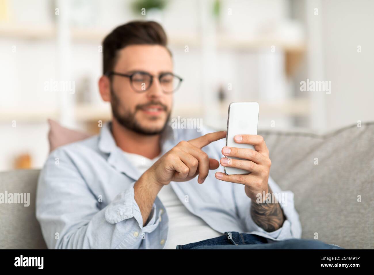 Handsome guy in eyeglasses using smatphone, touching screen while ...