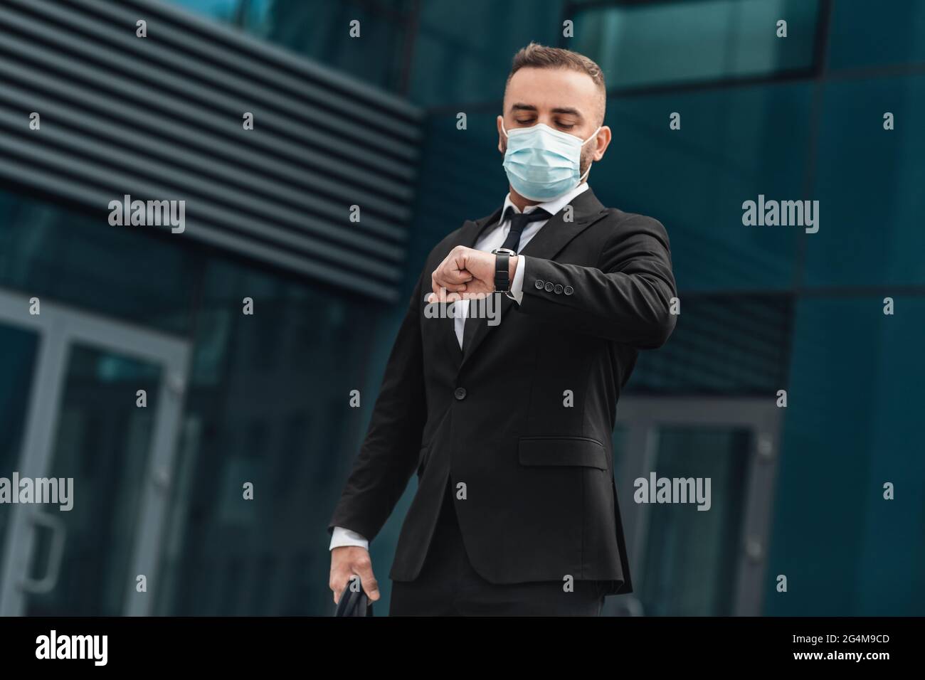 Handsome successful CEO looking at watch for time management, wearing ...