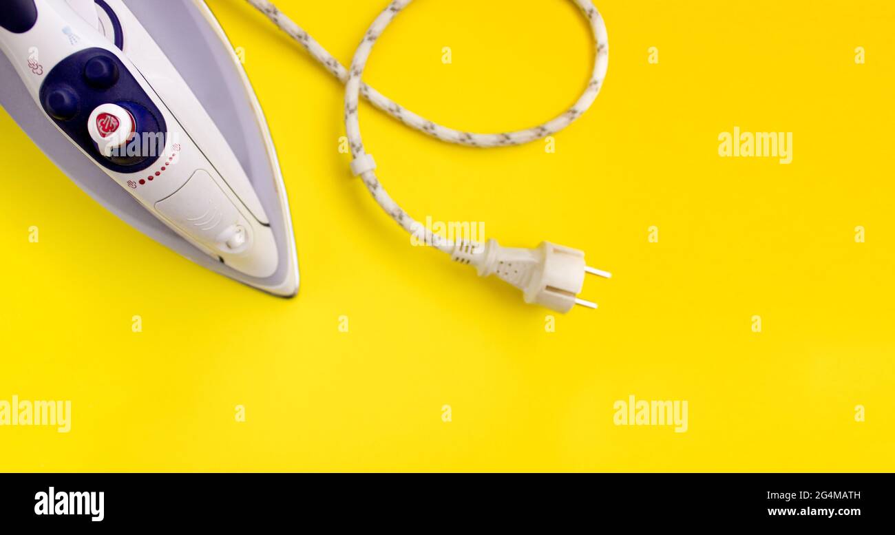 Iron for ironing things on a yellow background. Top view, copy space ...