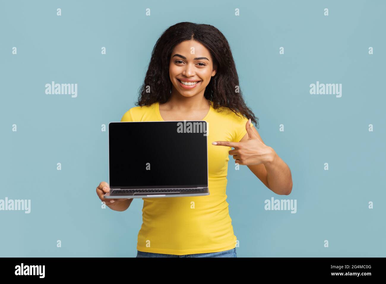 Online education. Cheerful black lady holding laptop computer in hand ...