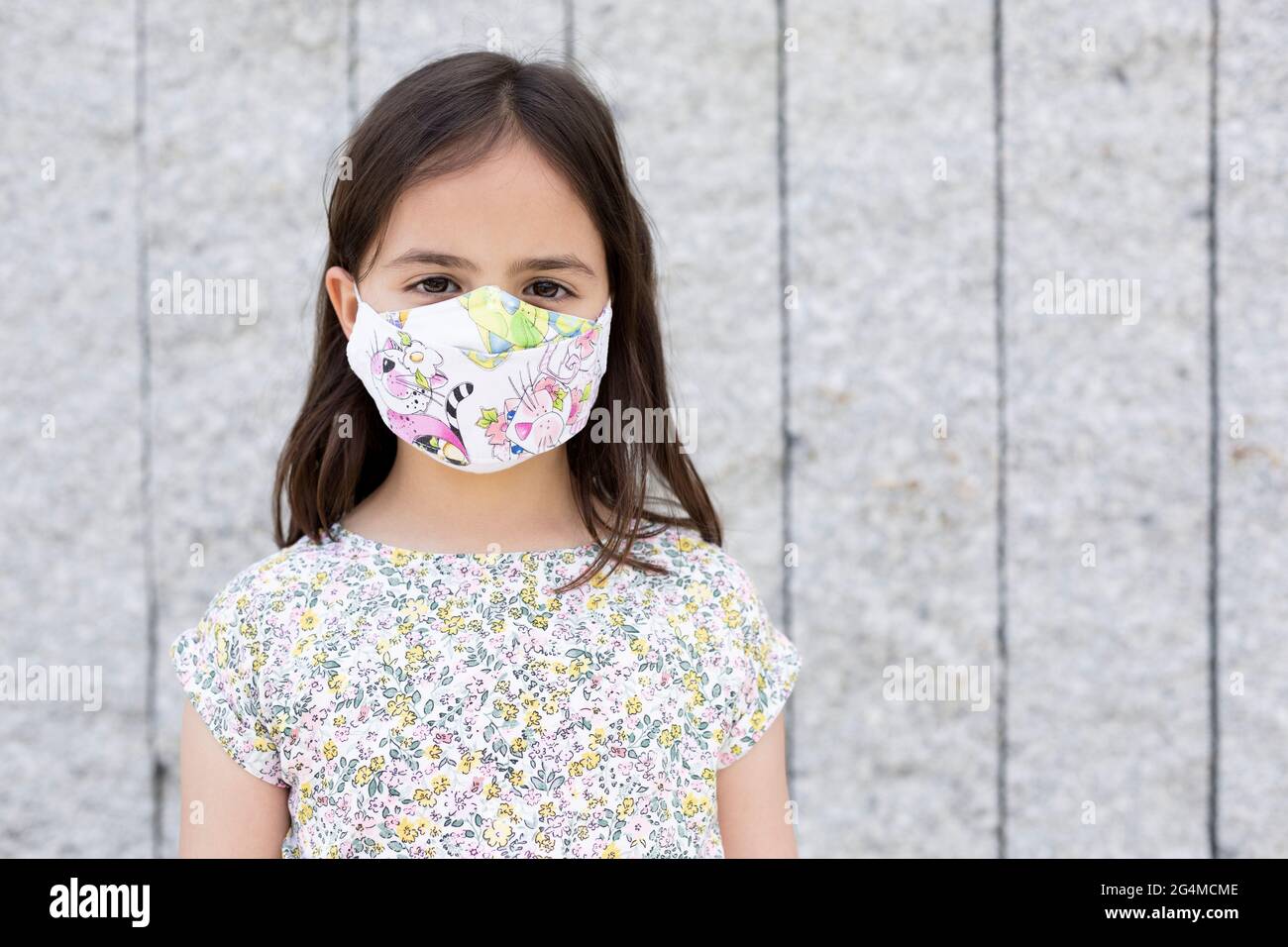 Portrait of little caucasian child with face mask. She is standing next ...