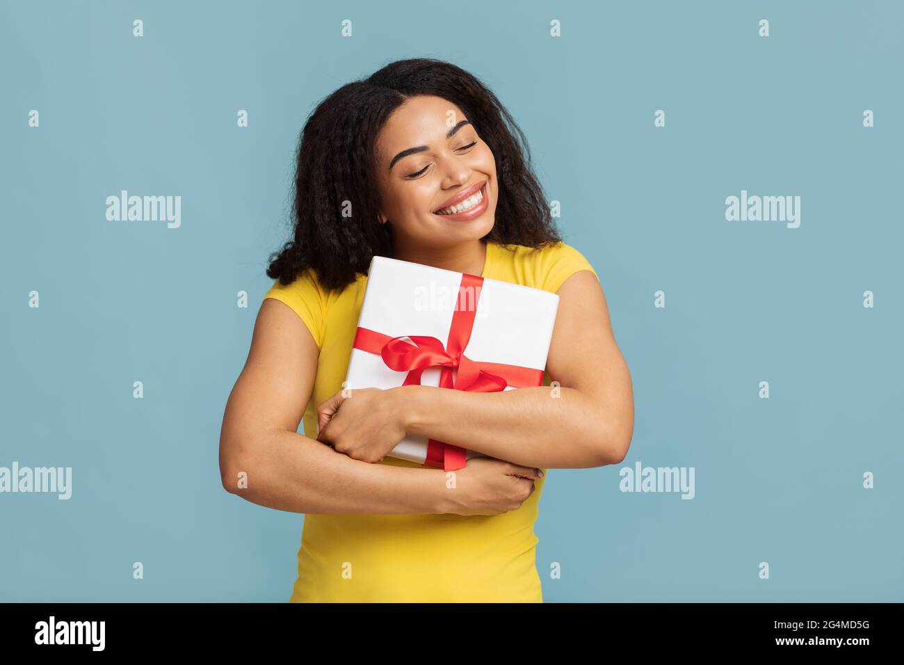 Best present. Joyful african american lady hugging gift box posing over ...