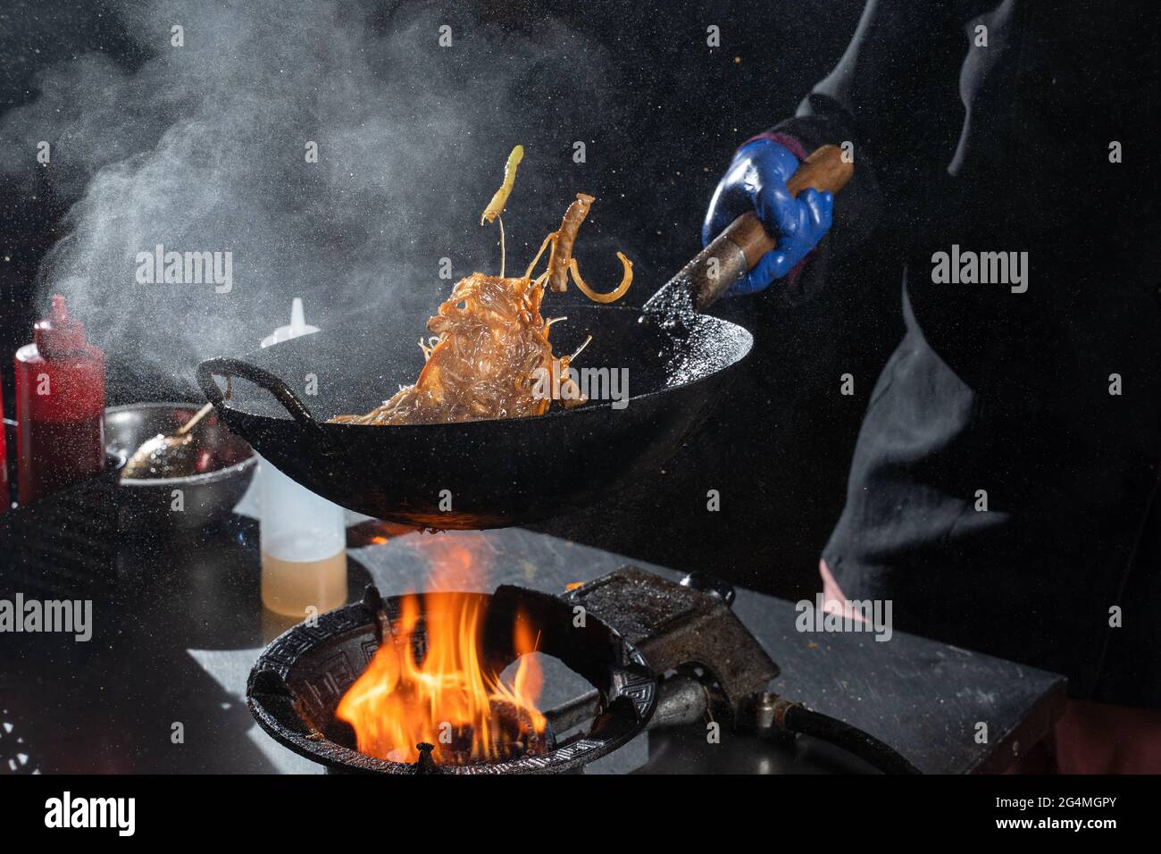 Flying flambe noodles for wok box with meat, soy sauce fried in a wok ...