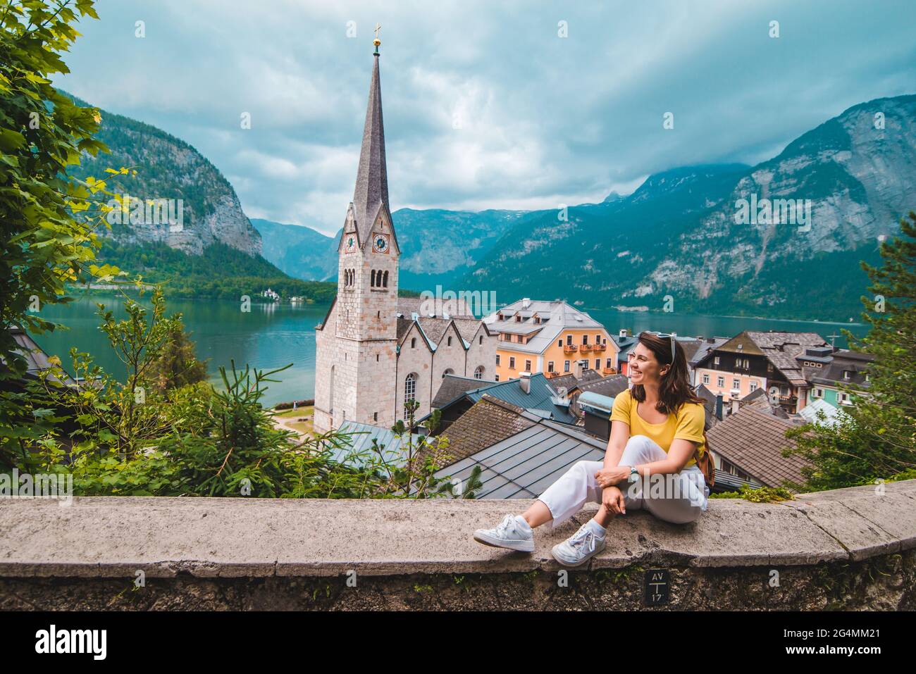 woman with backpack sitting and enjoying the vie of hallstatt austria ...