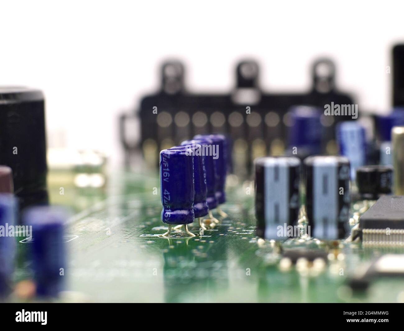 four electrolytic capacitors mounted on printed circuit board in a row ...