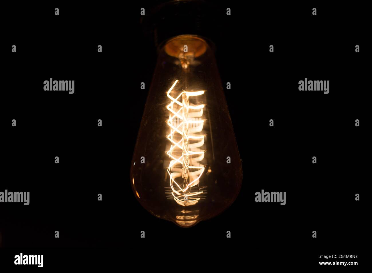 Edison lamp with warm light sways lightly on a black background Stock ...