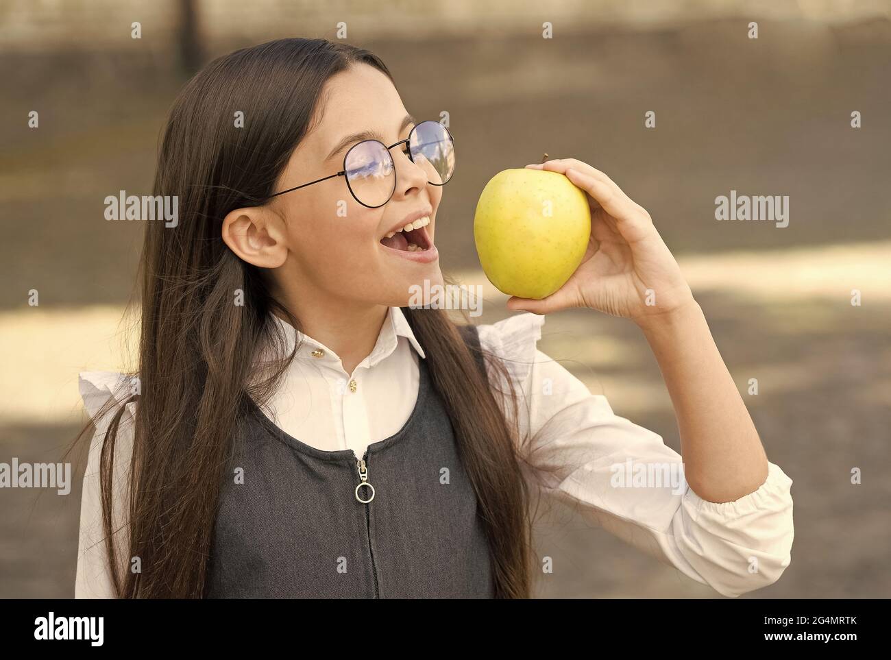 Healthy dose of vitamin C. Happy kid eat apple outdoors. School snack ...