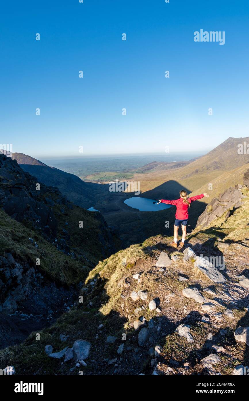 A happy woman raising her arms on top of devils ladder with two lakes ...