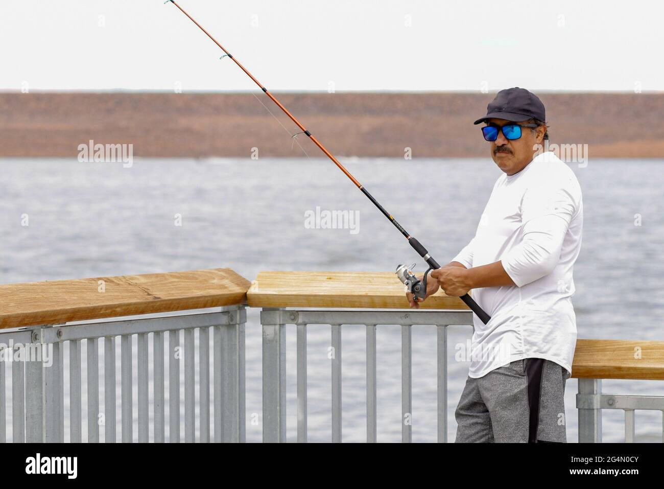 Side view of an adult Hispanic male happily fishing on the bay Stock ...