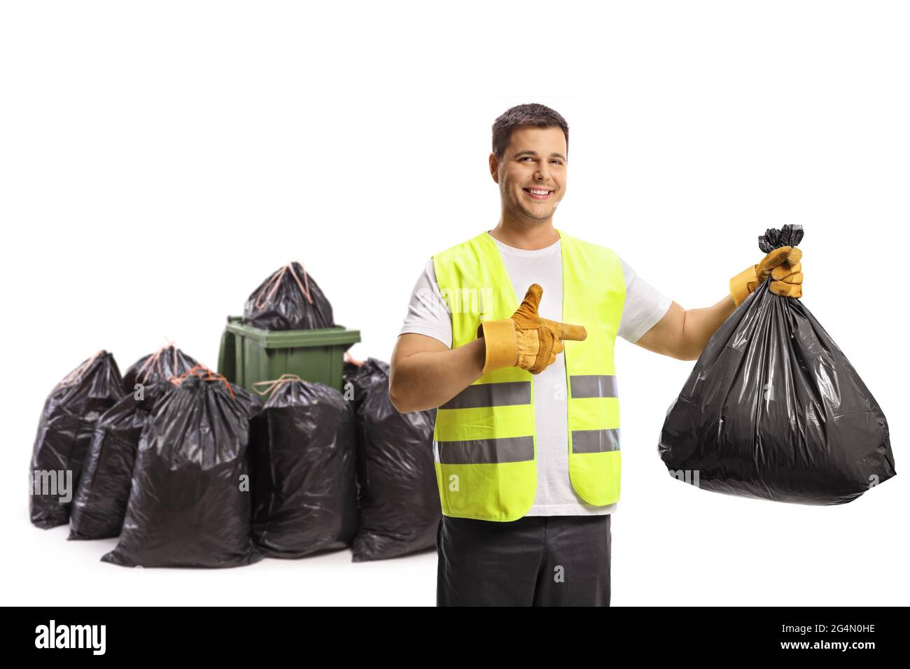 Garbageman holding a plastic bag in front of a bin and a pile of bags ...